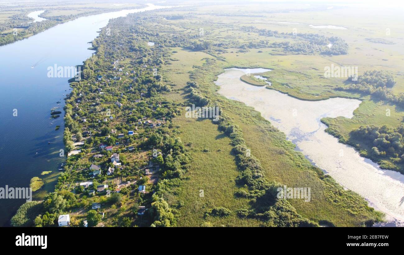 Drone fly over waving river surrounded by local village with various ...