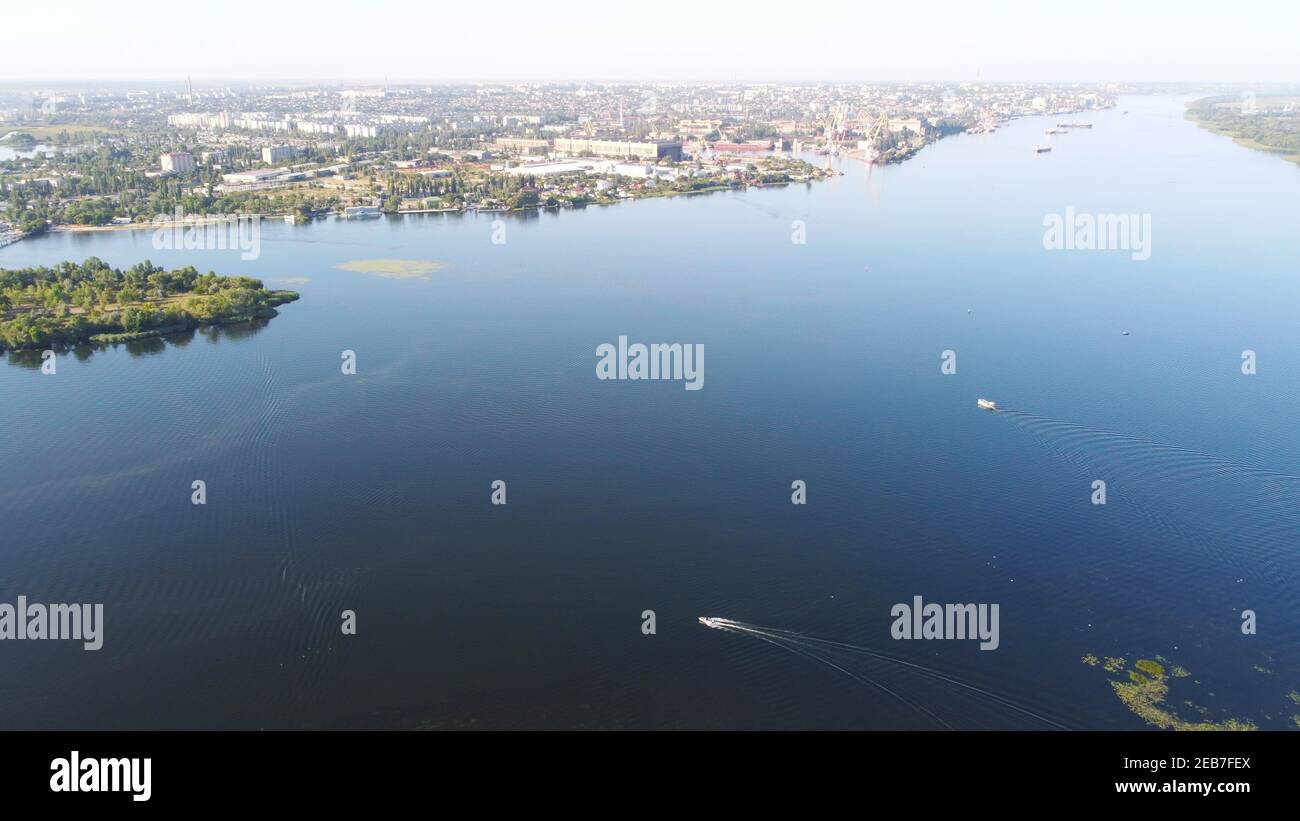 Drone fly over waving river surrounded by local village with various ...