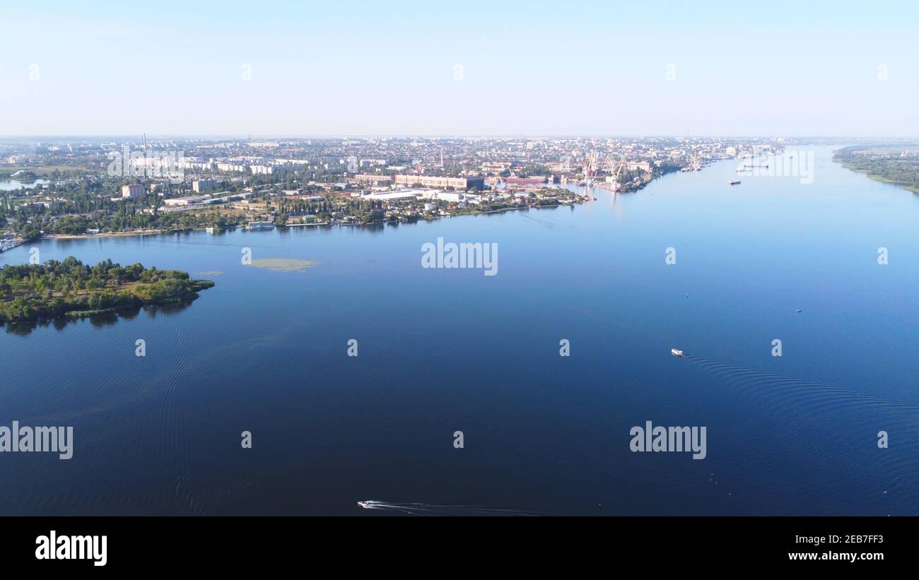 Drone fly over waving river surrounded by local village with various ...