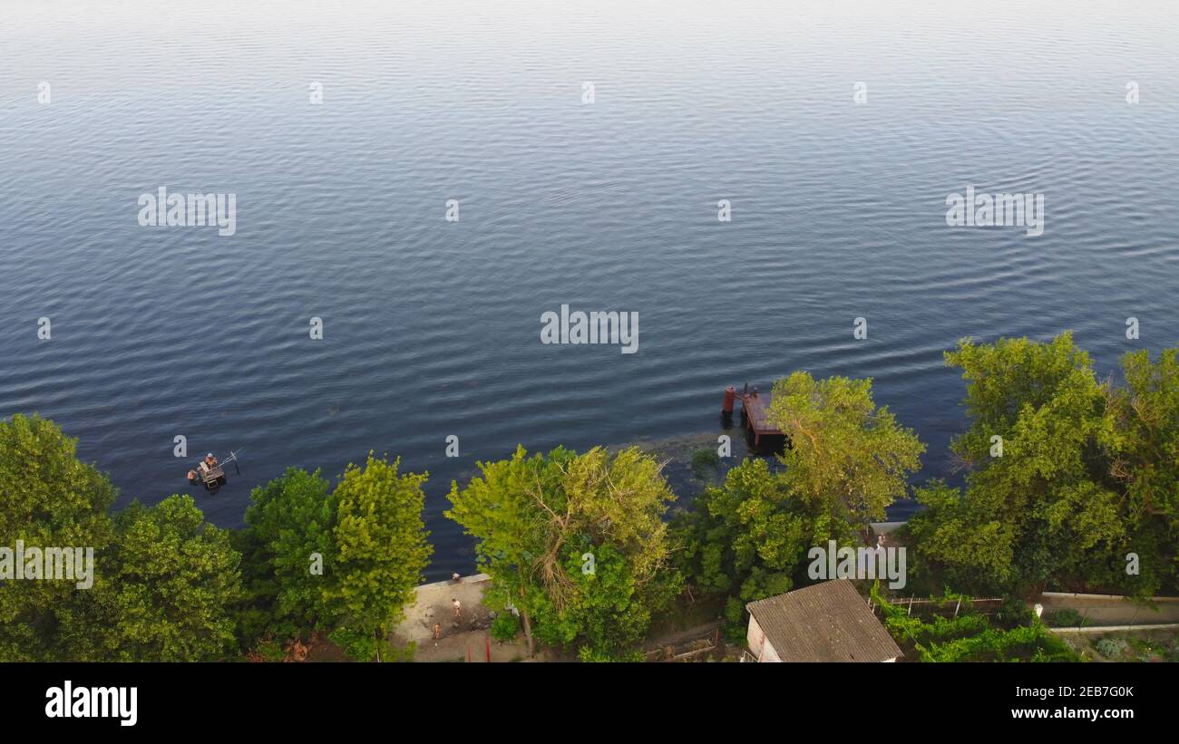 Drone fly over waving river surrounded by local village with various ...