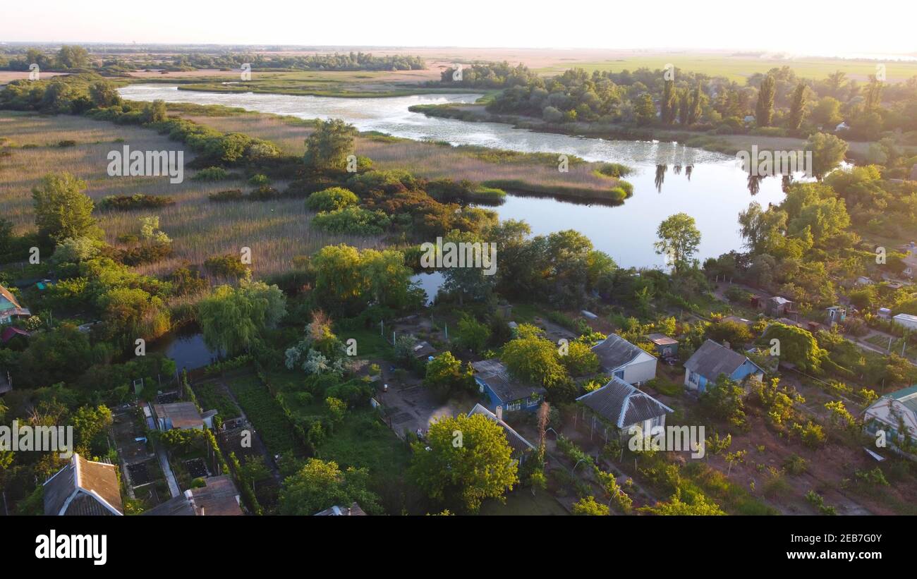 Drone fly over waving river surrounded by local village with various ...