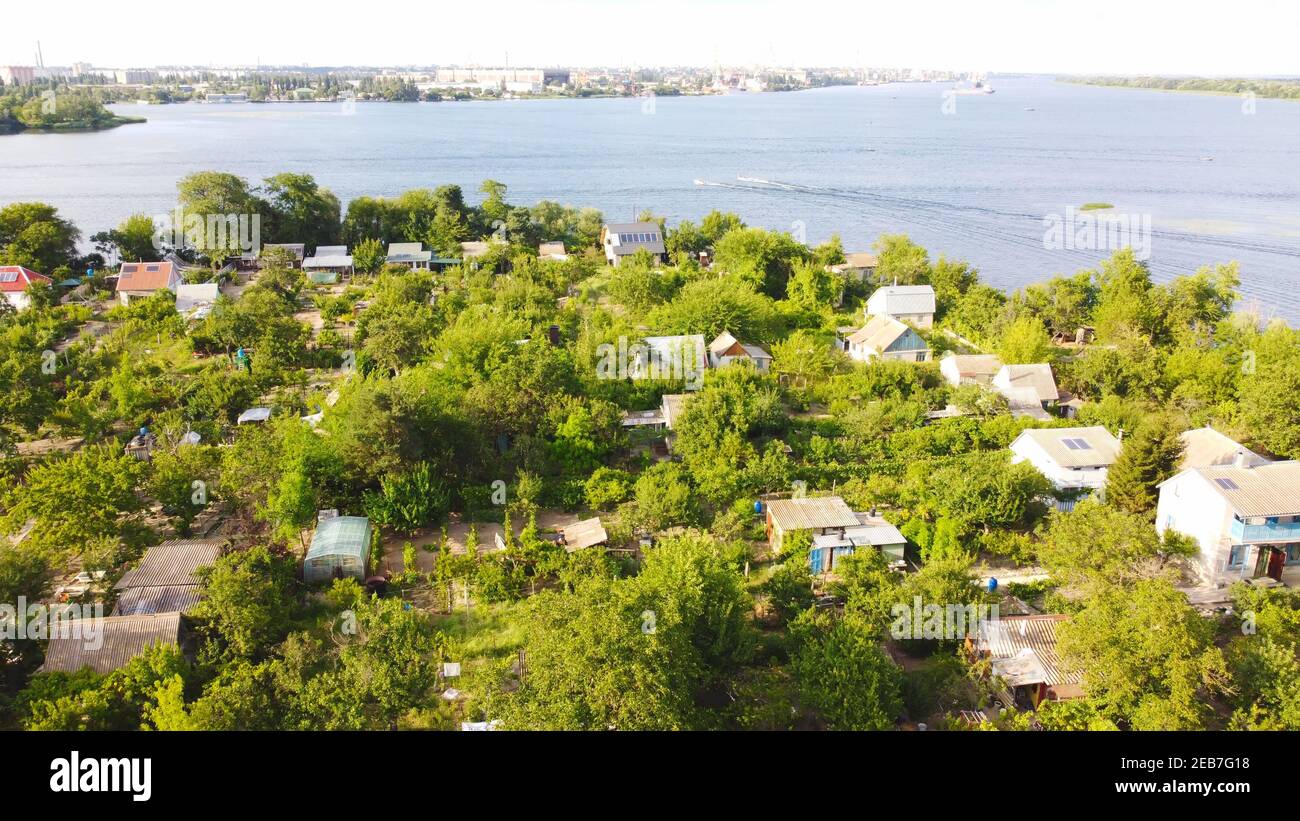 Drone fly over waving river surrounded by local village with various ...