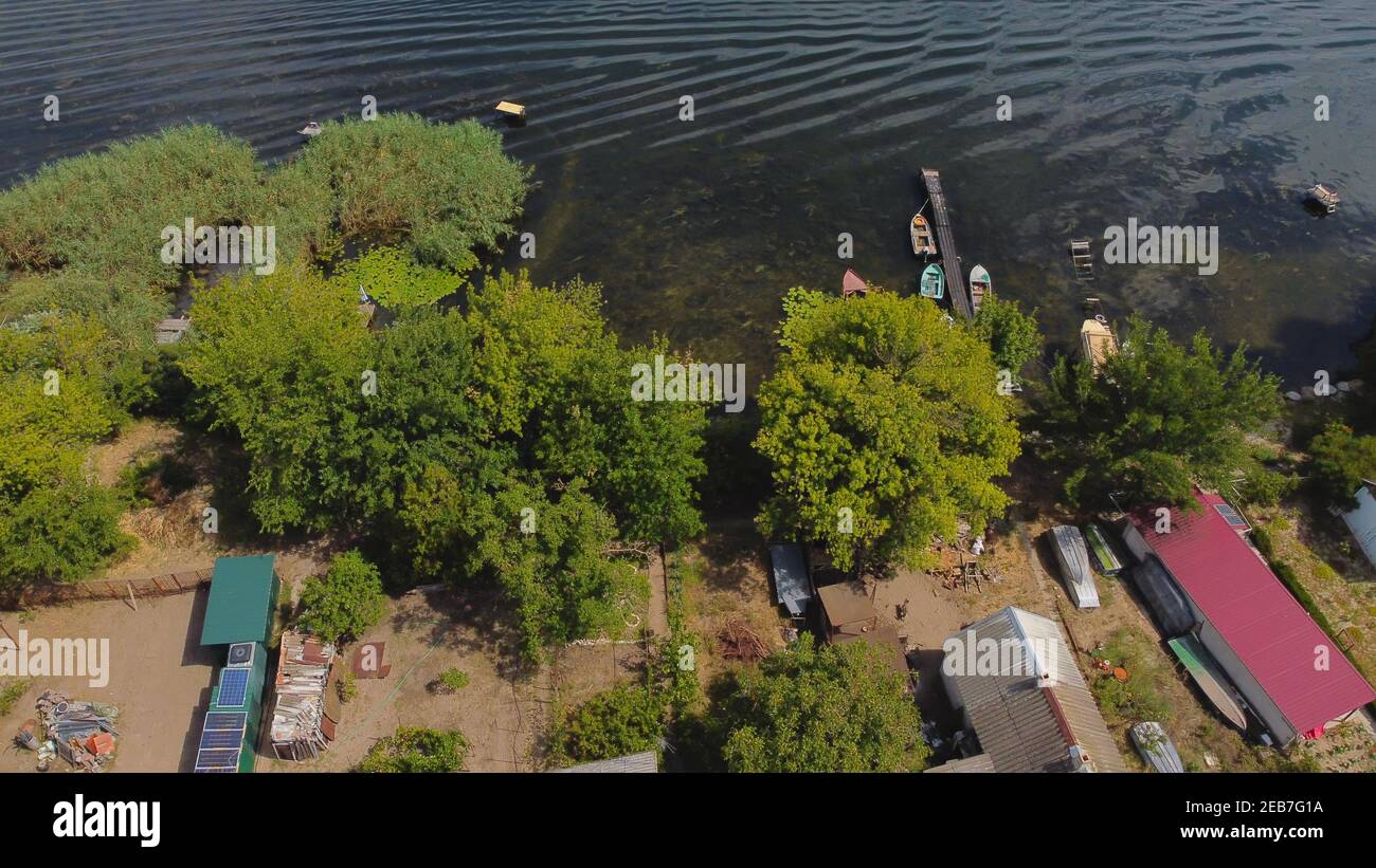 Drone fly over waving river surrounded by local village with various ...