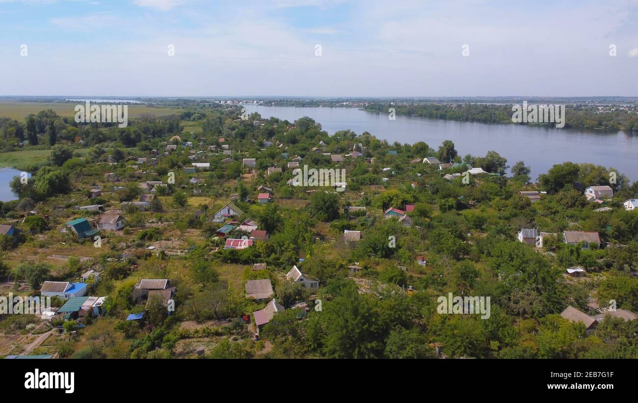 Drone fly over waving river surrounded by local village with various ...