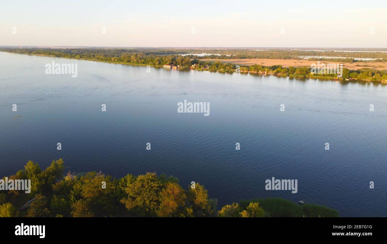 Drone fly over waving river surrounded by local village with various ...