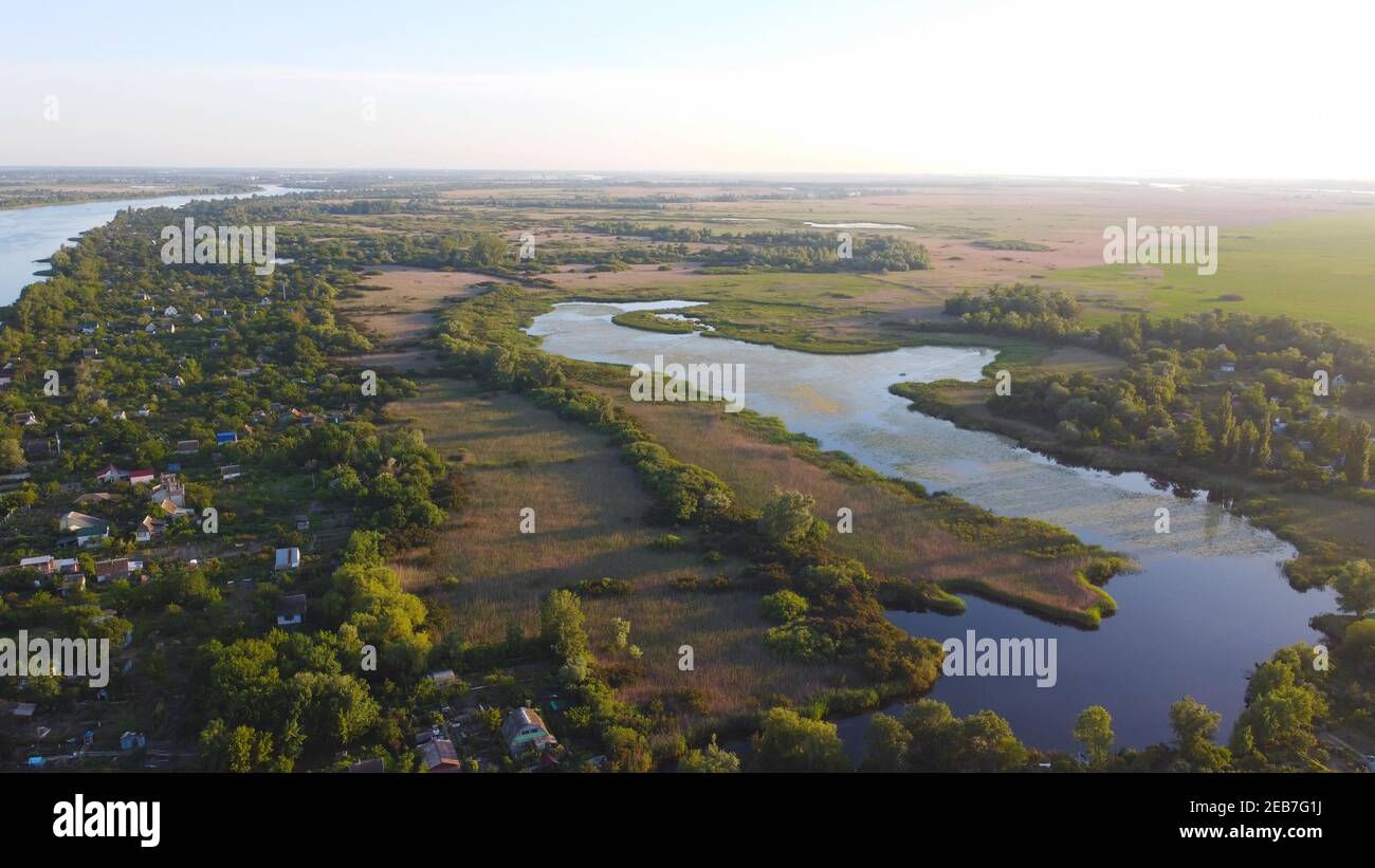 Drone fly over waving river surrounded by local village with various ...