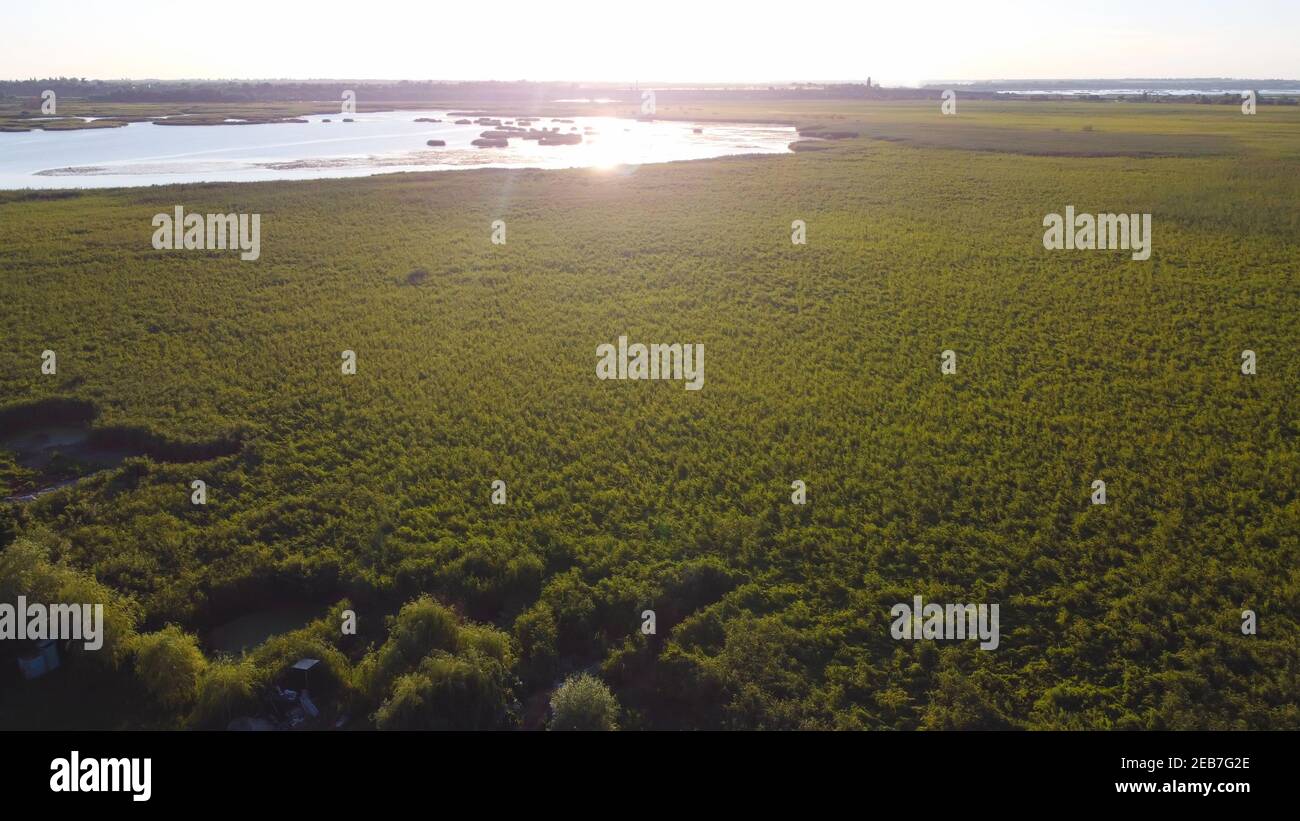 Drone fly over waving river surrounded by local village with various ...