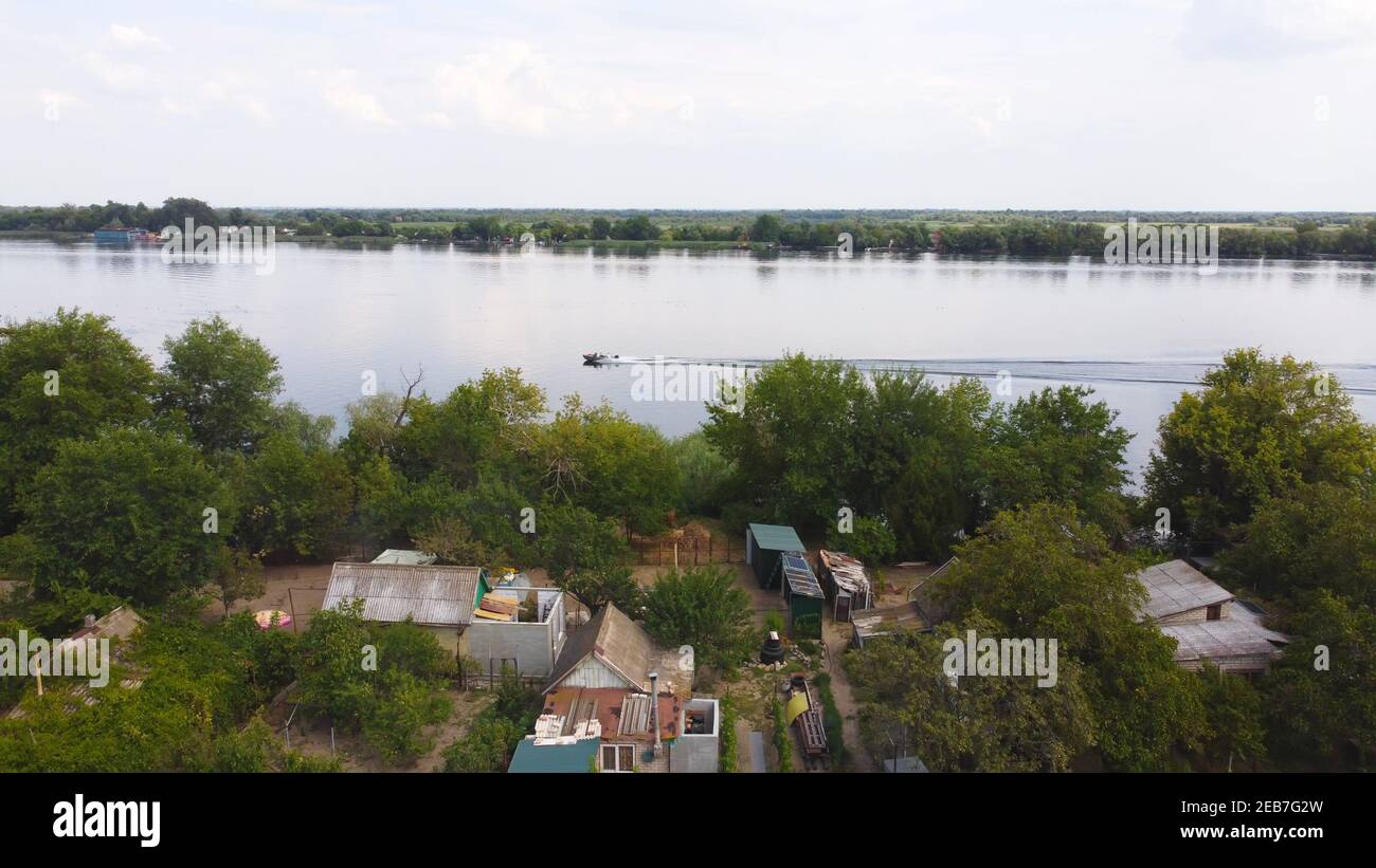 Drone fly over waving river surrounded by local village with various ...