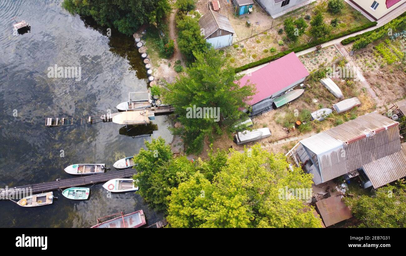Drone fly over waving river surrounded by local village with various ...