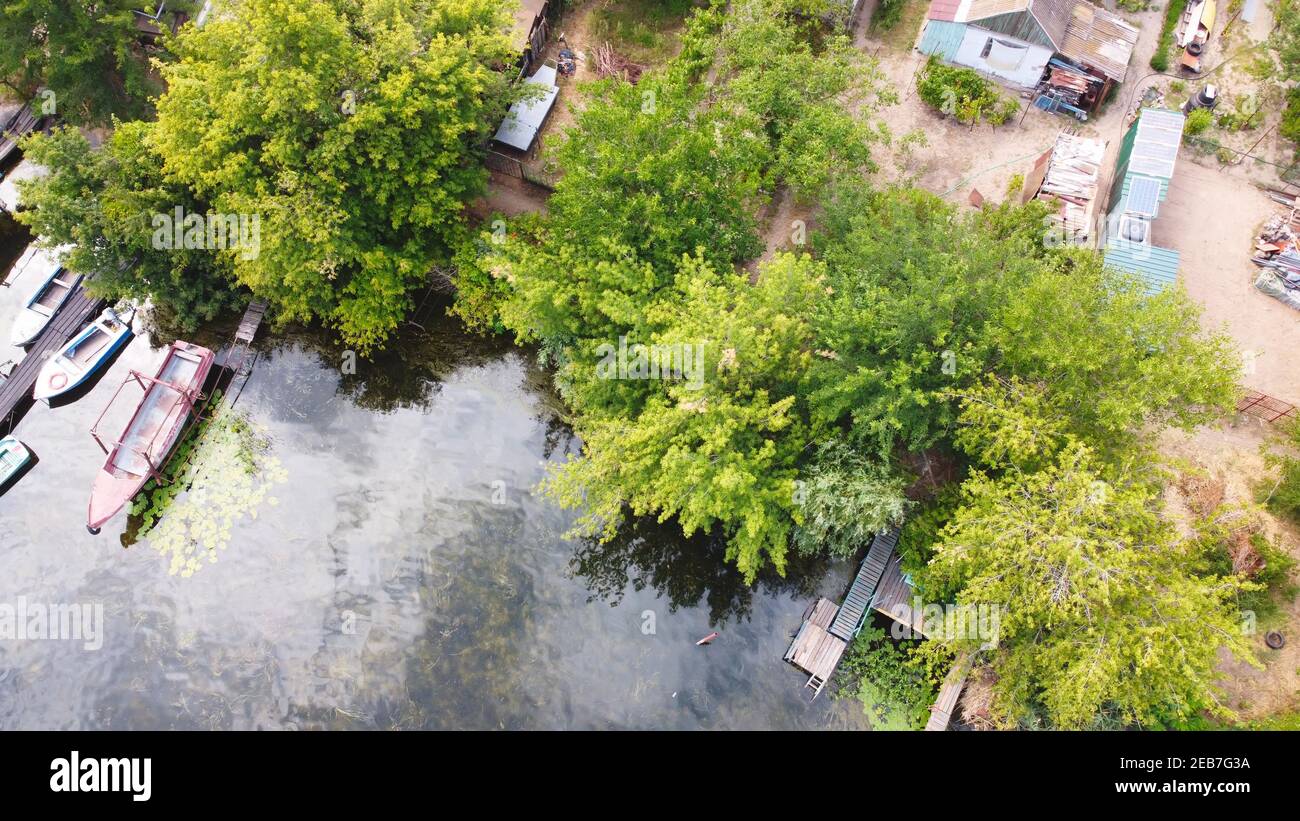 Drone fly over waving river surrounded by local village with various ...