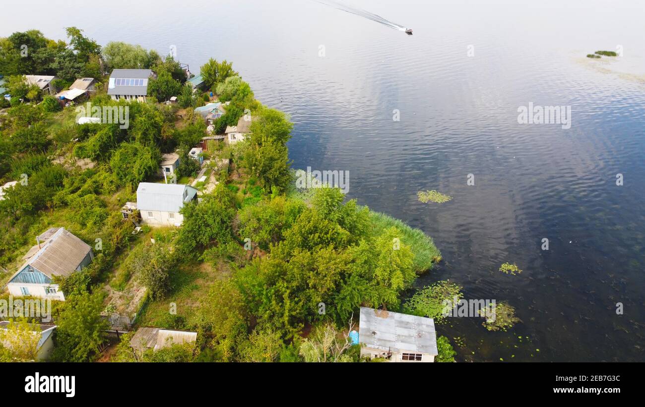 Drone fly over waving river surrounded by local village with various ...