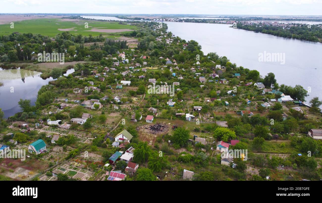 Drone fly over waving river surrounded by local village with various ...