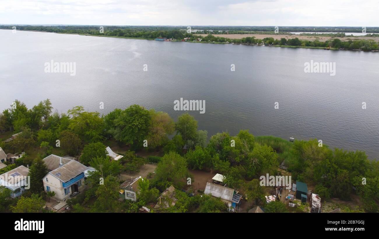 Drone fly over waving river surrounded by local village with various ...