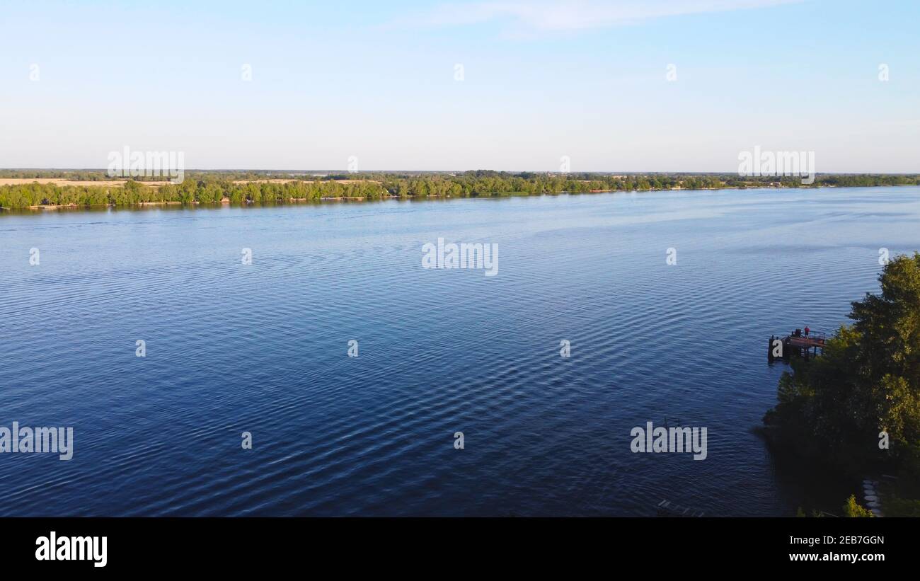 Drone fly over waving river surrounded by local village with various ...