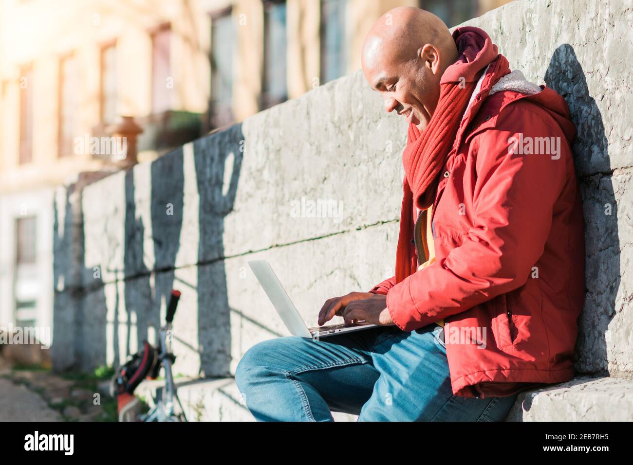 Happy smiling Hispanic male using a laptop computer while leaning on a ...