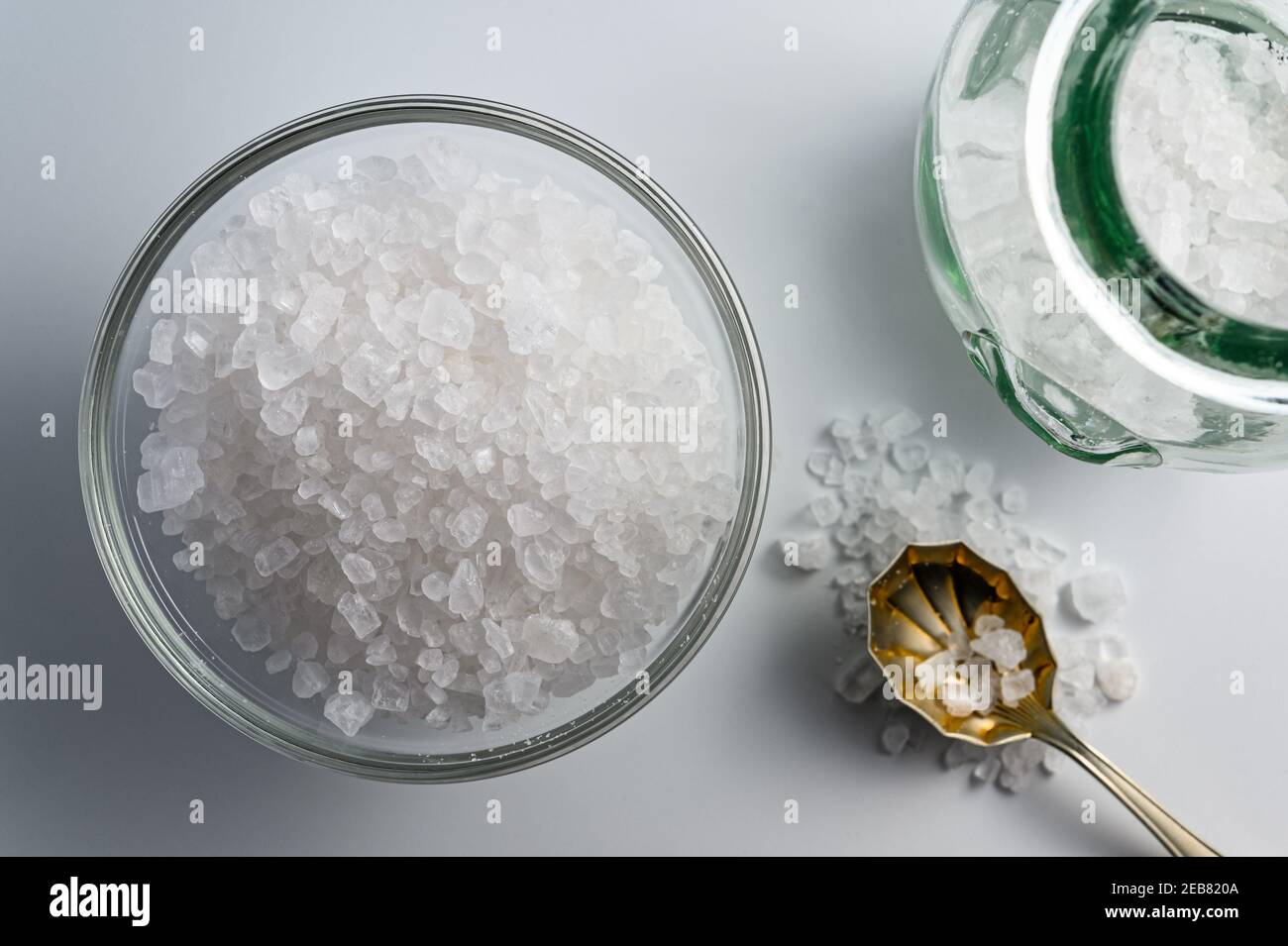 Glass jar and bowl of sea salt on white background Stock Photo - Alamy