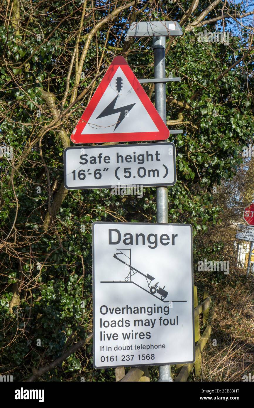Warning sign at a level crossing for low live wires saying danger ...