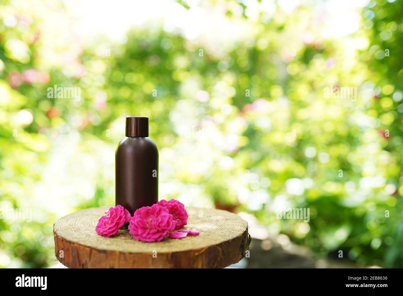 Essential oil with pink flowers on wooden table on blur fresh herbs ...