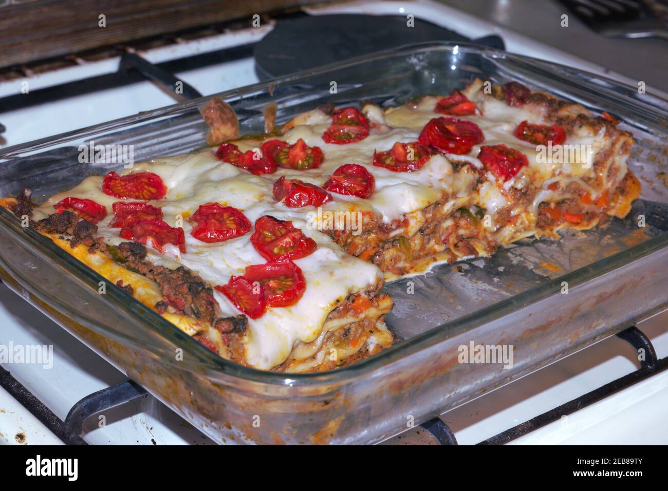 homemade lasagna with cherry tomatoes in glass baking dish, on stovetop ...