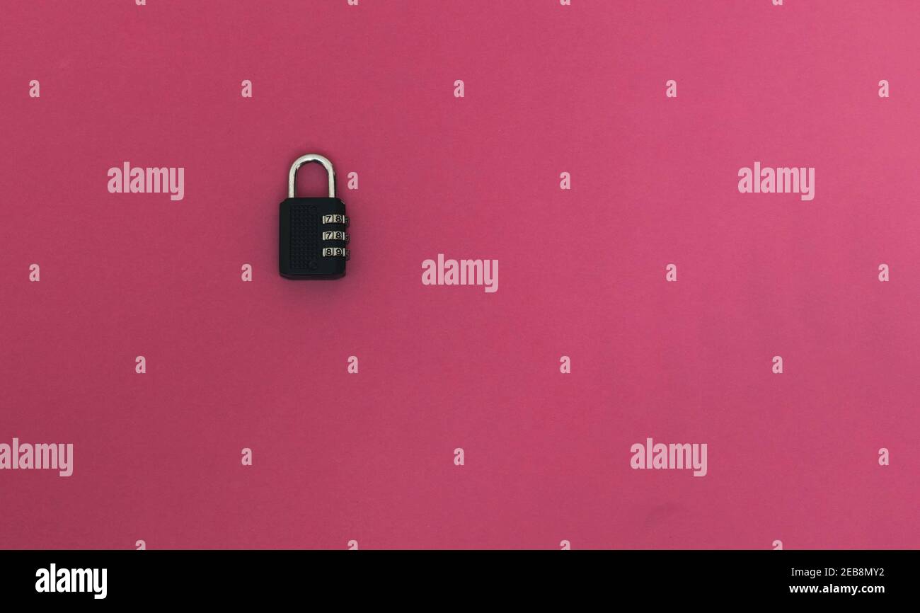 detail of a black padlock with a combination of numbers closed on pink ...