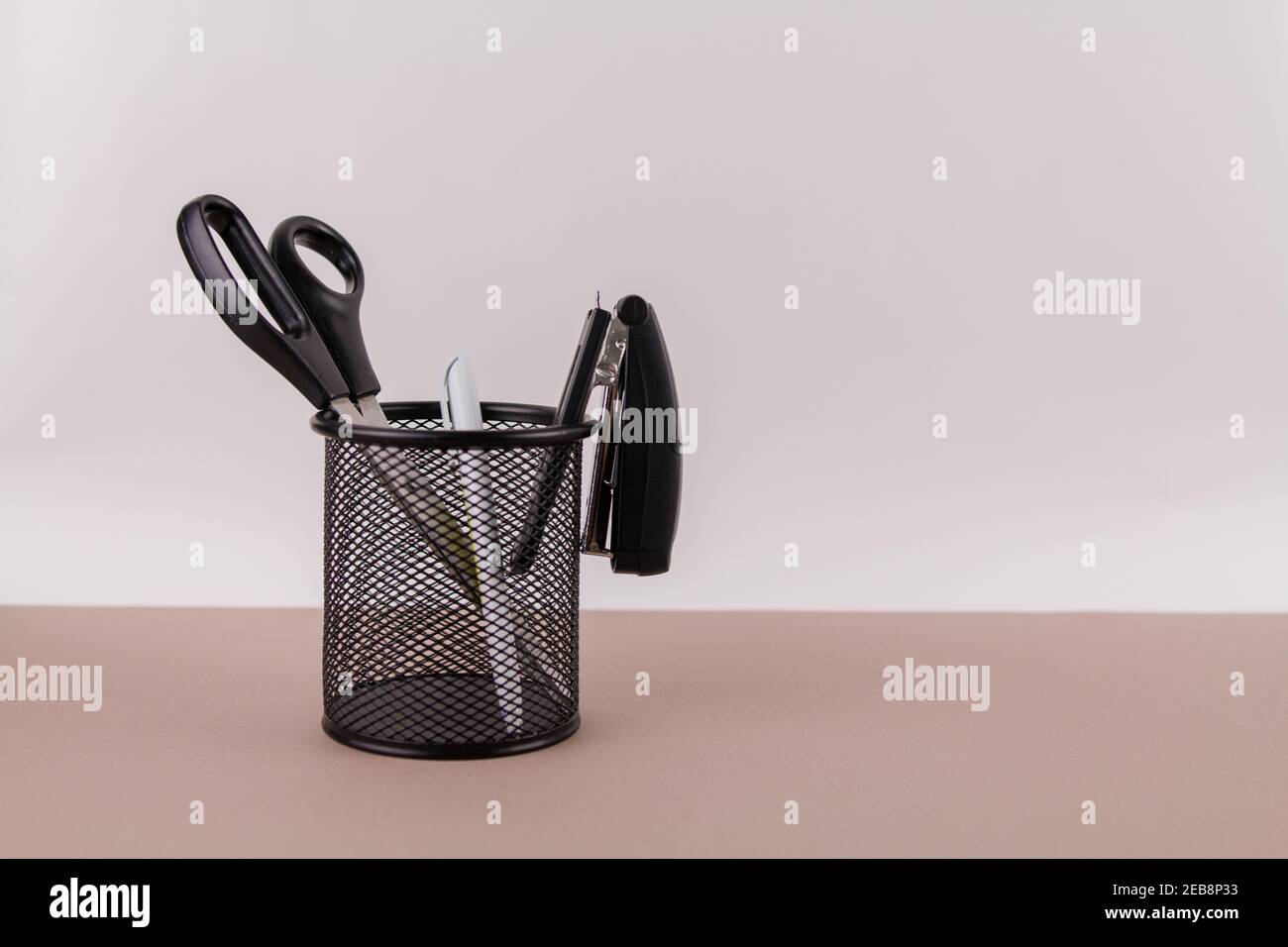 a scissors and a stapler with a handle in an organizer on a white ...