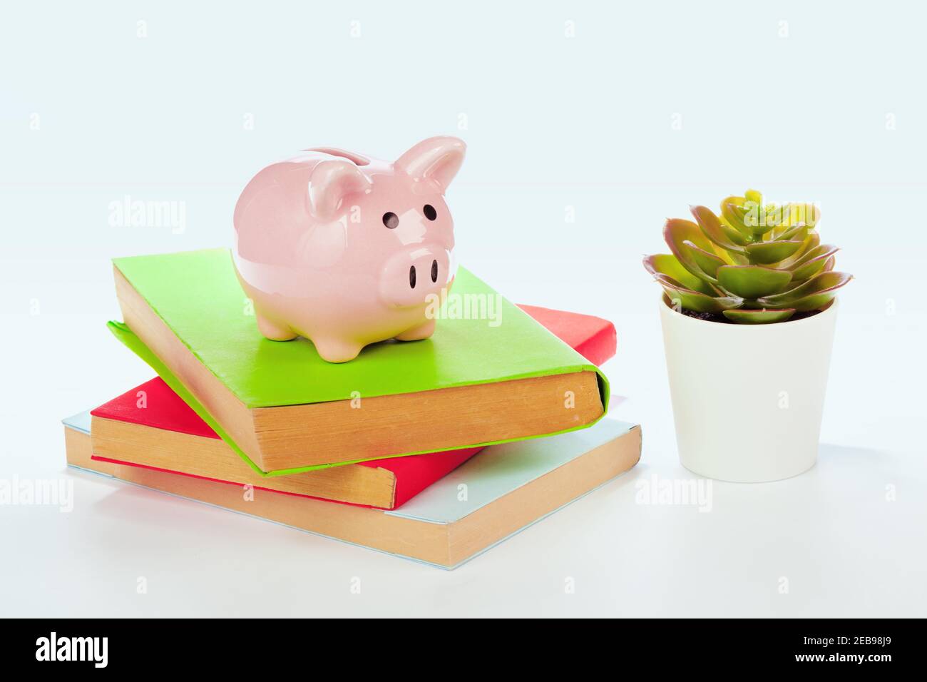 piggy bank over a stack of colorful books Stock Photo - Alamy