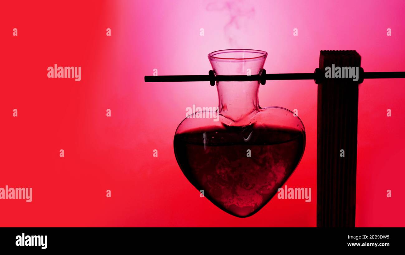 Open heart-shaped bottle of red love potion on a blurredred and pink ...