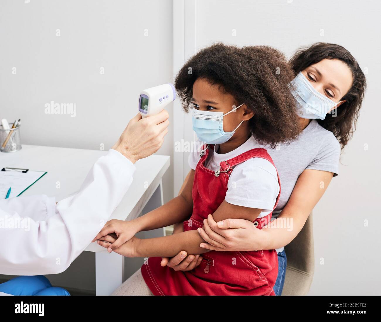 Pediatrician checking body temperature of a child using a non-contact ...