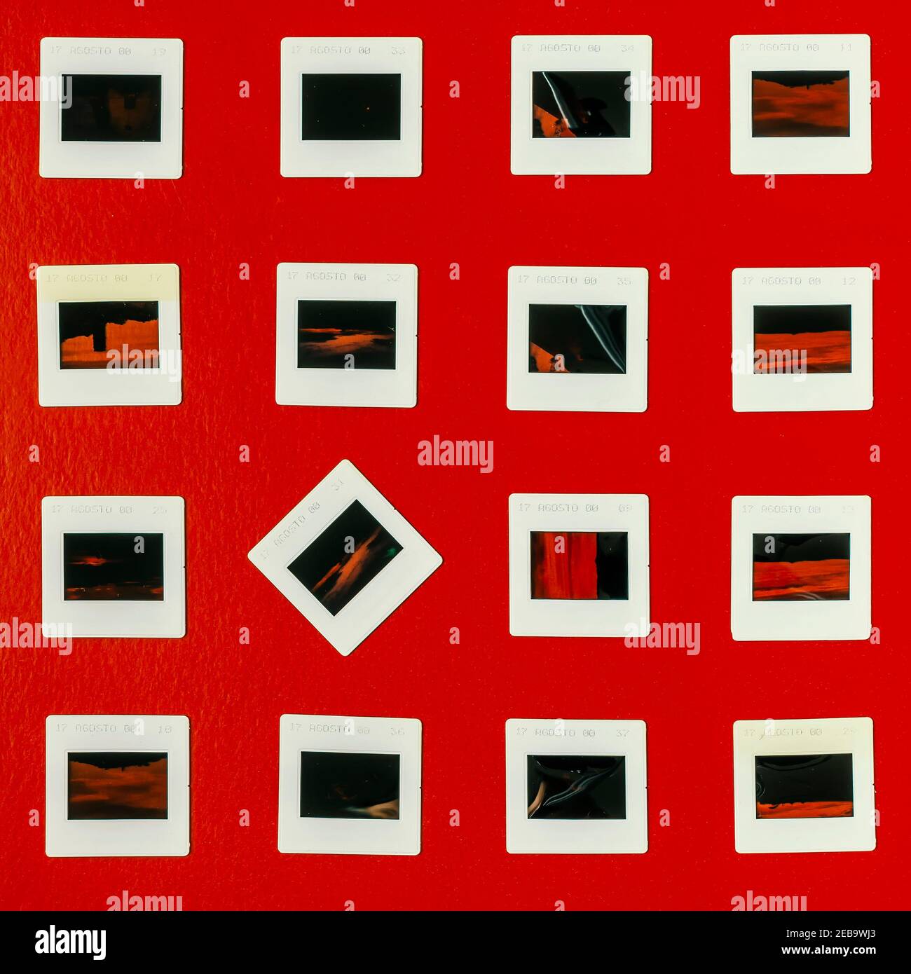 A square made up of four rows of old photographic slides on a red ...