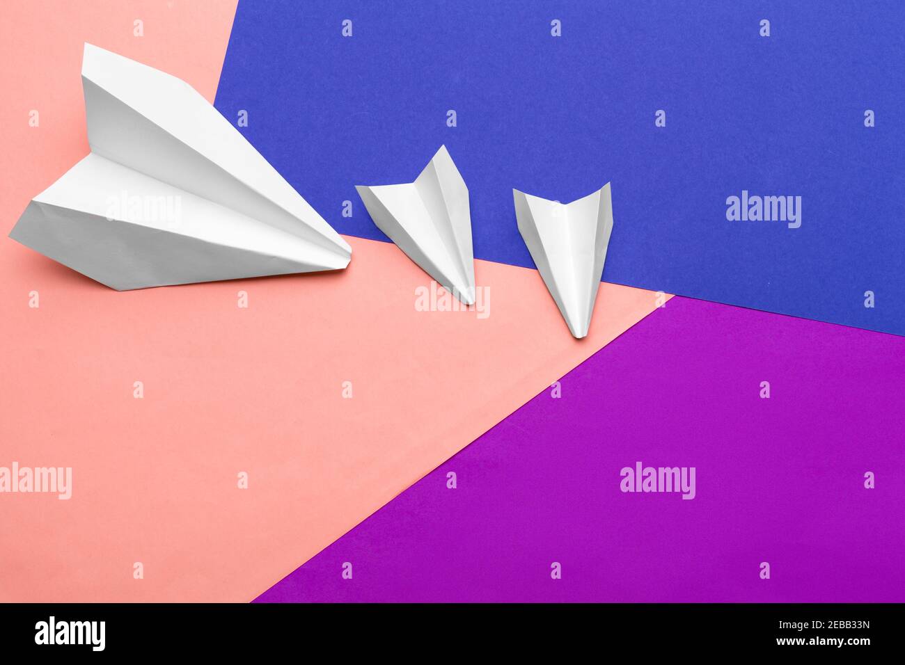 white paper airplane on a color block paper background Stock Photo - Alamy