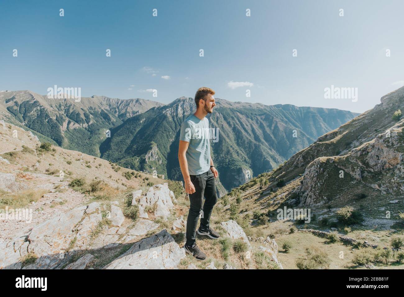 Shallow focus of a young male standing on rocky hills under the ...