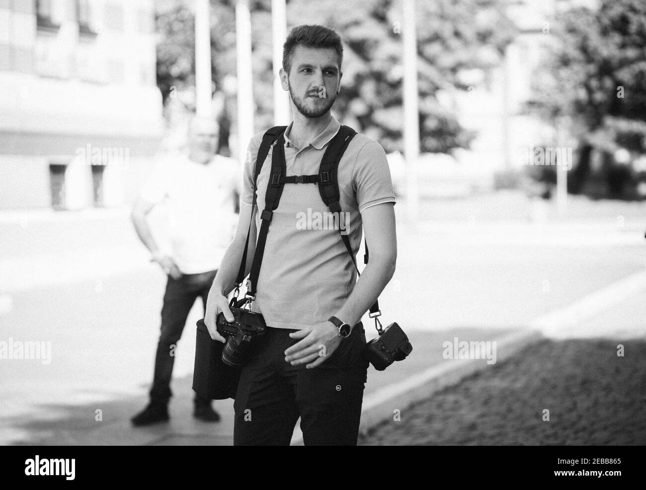 Grayscale portrait of a young male photographer with cameras in Stock ...