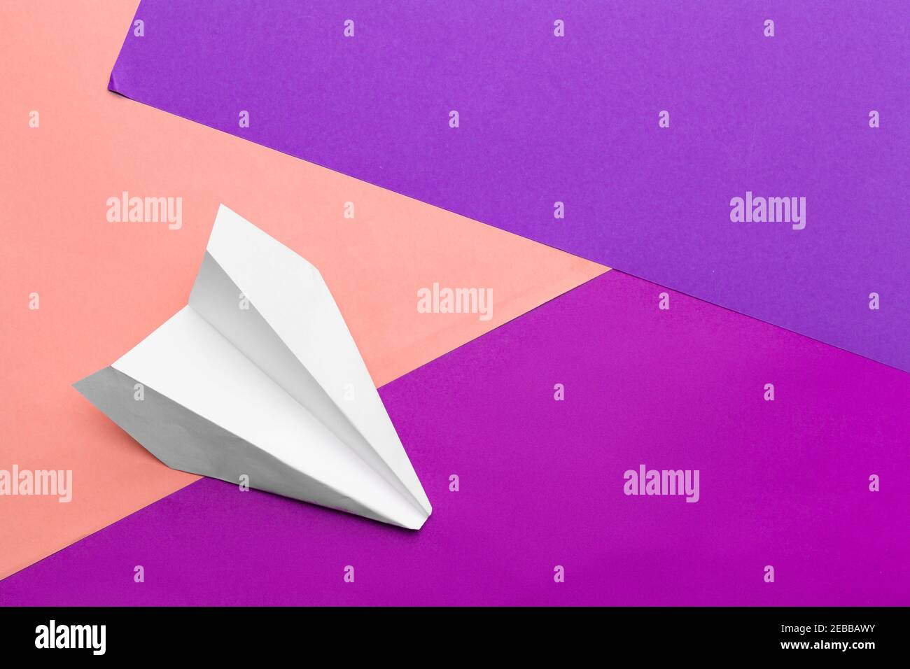 white paper airplane on a color block paper background Stock Photo - Alamy