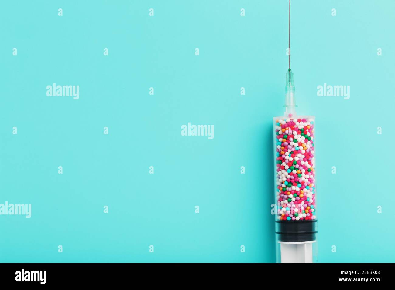 Syringe filled with colorful nano balls on a light blue background ...