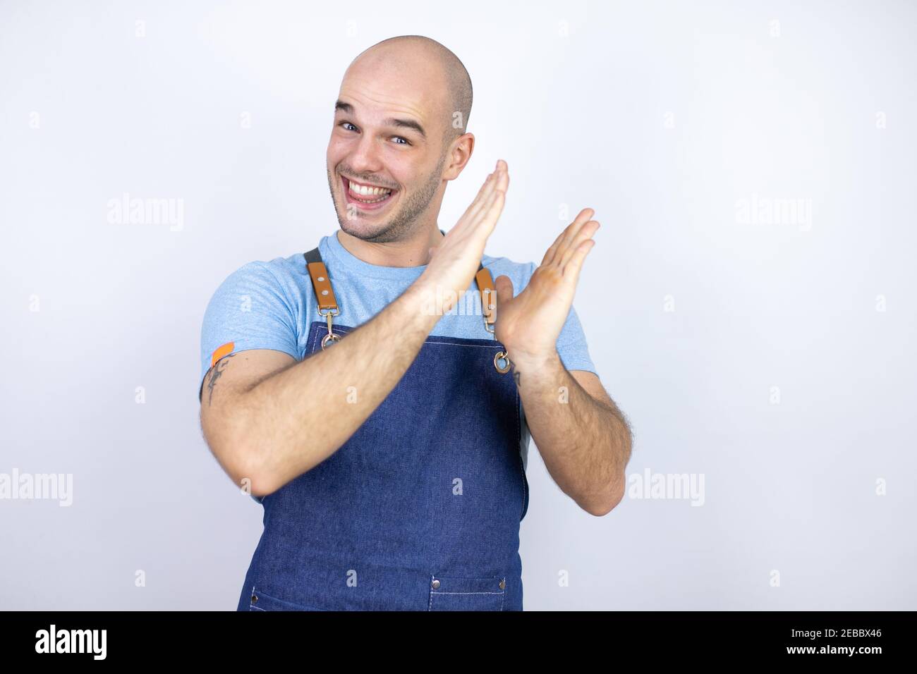 Young bald man wearing apron uniform over isolated white background ...