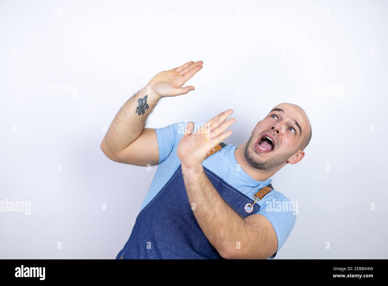 Young bald man wearing apron uniform over isolated white background ...