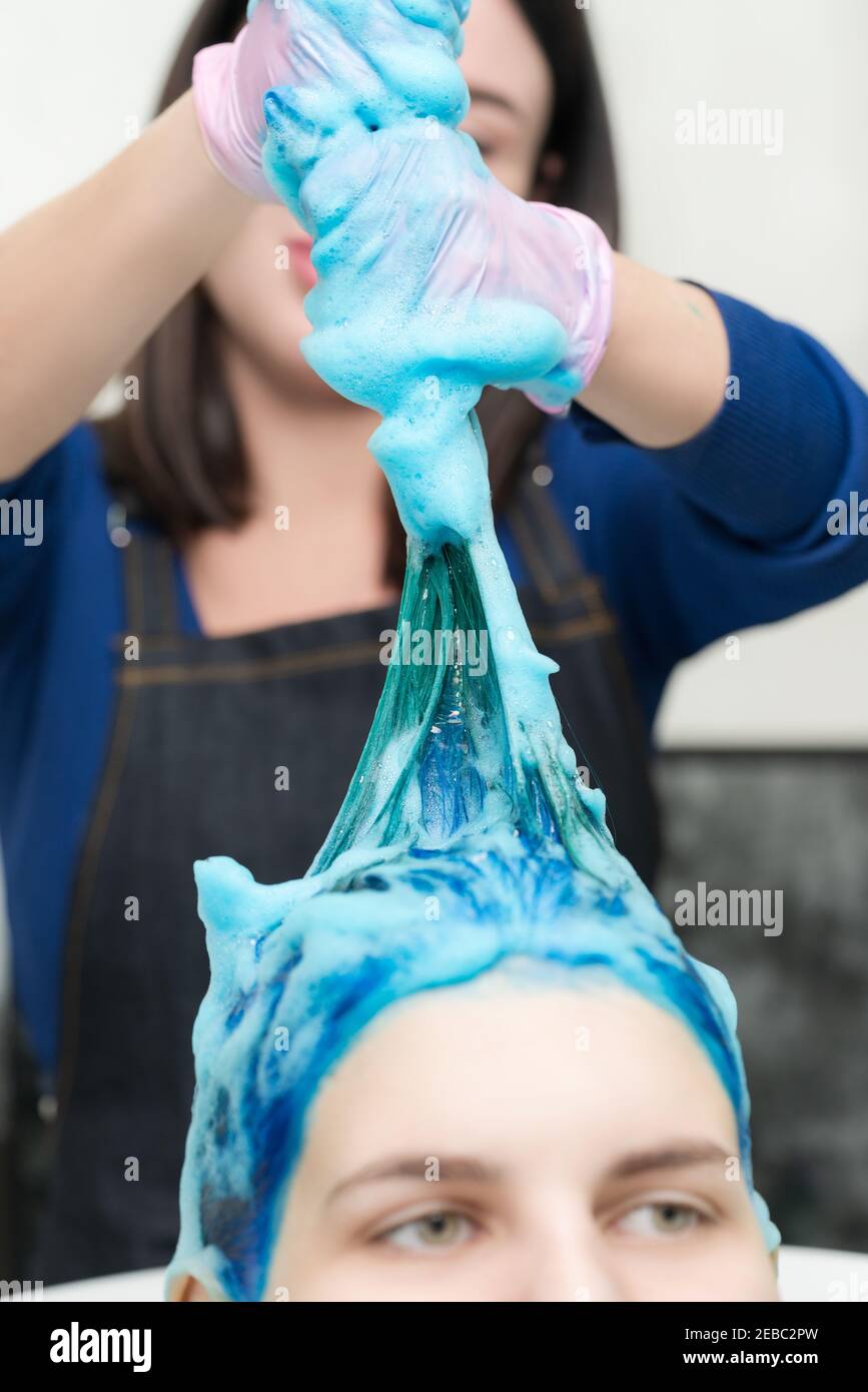 Professional hairdresser washes female head with sapphire hair color ...