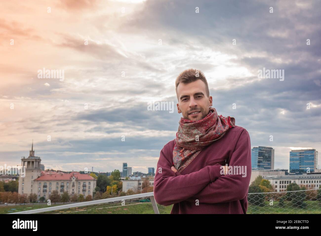 Portrait of handsome man with crossed arms at dramatic sky and urban ...