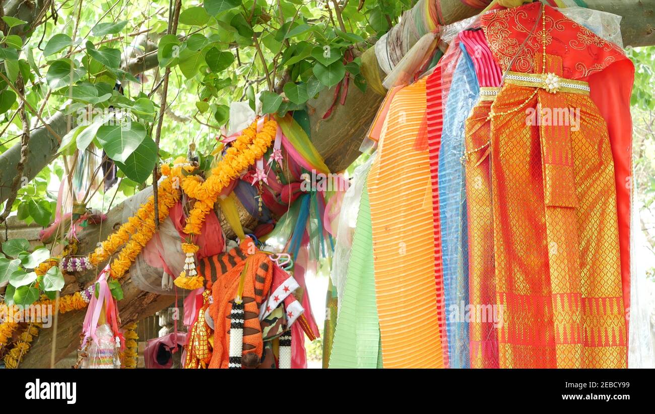 Colorful offering clothes on tree near altar. Bunch of bright ...