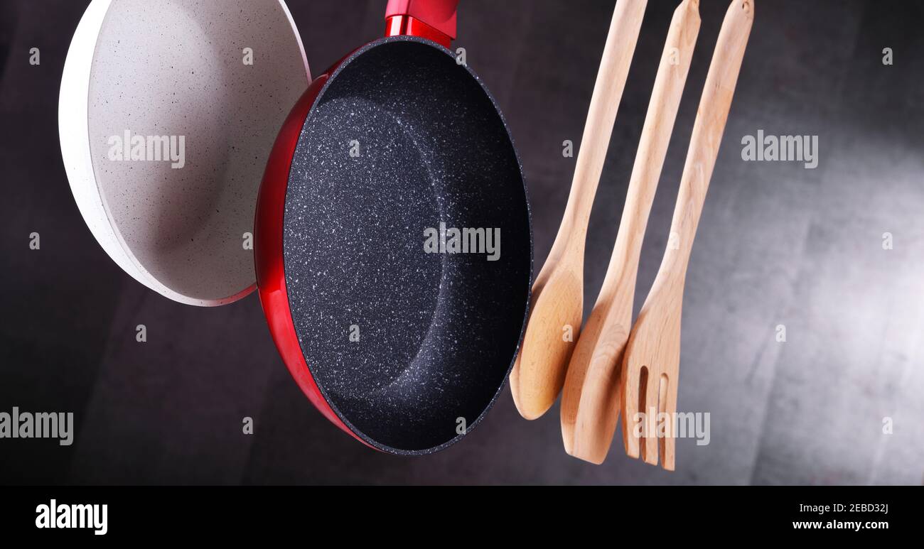Two hanging frying pans and kitchen utensils Stock Photo - Alamy
