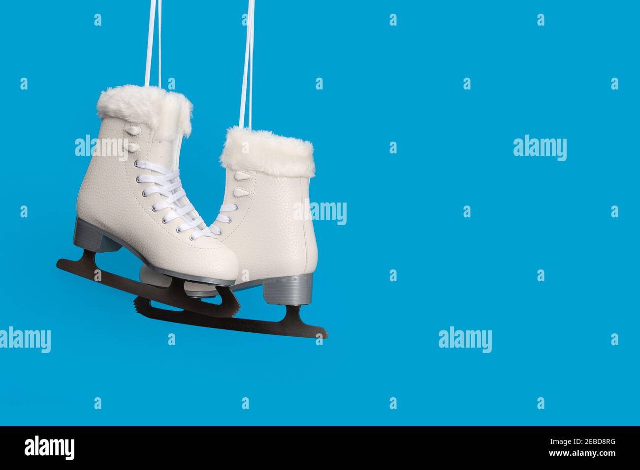 Pair of white figure ice skates on a blue background with space for ...