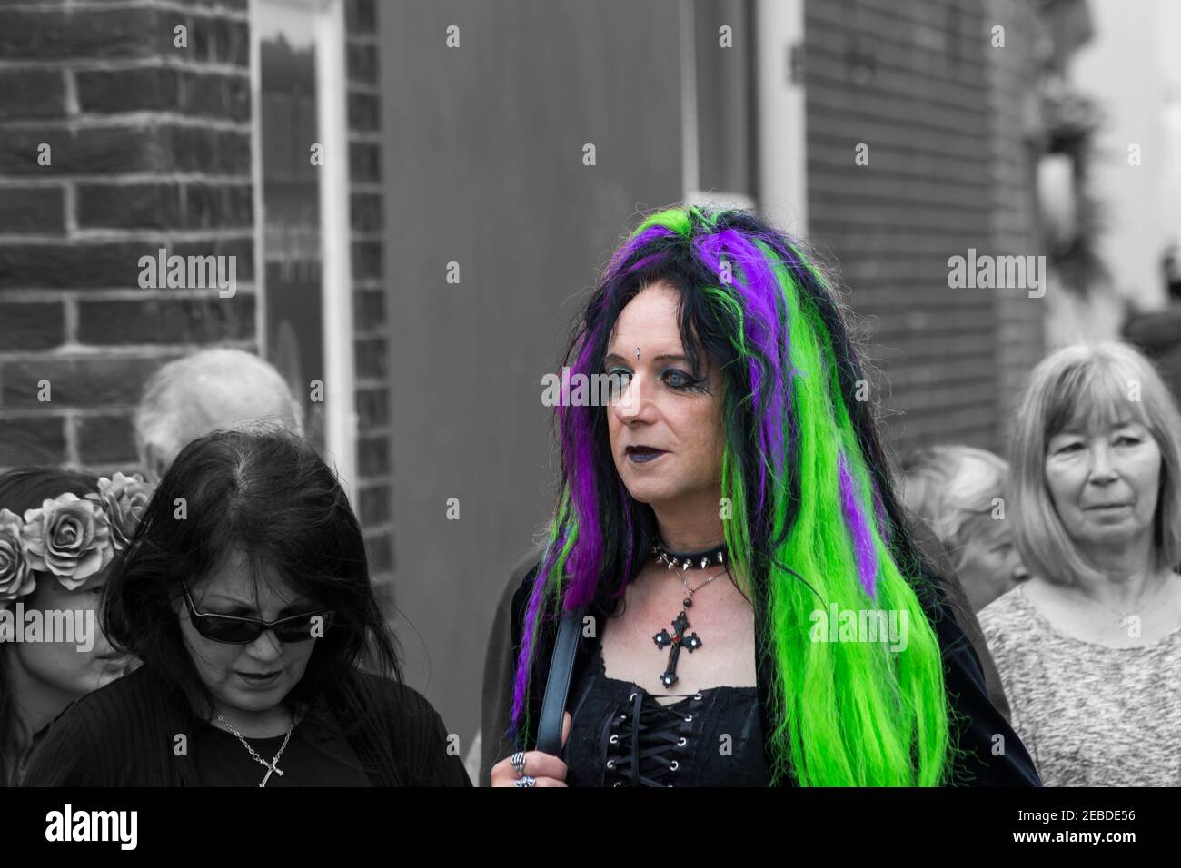 Goth woman with bright green and purple hair wearing cross at Wimborne ...