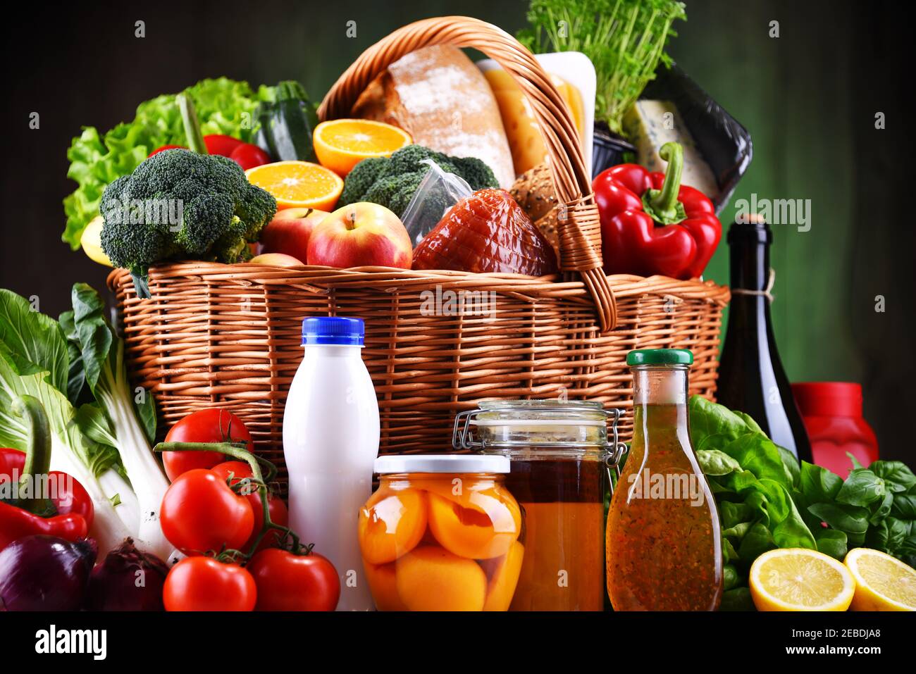 Wicker basket with assorted grocery products including fresh vegetables ...