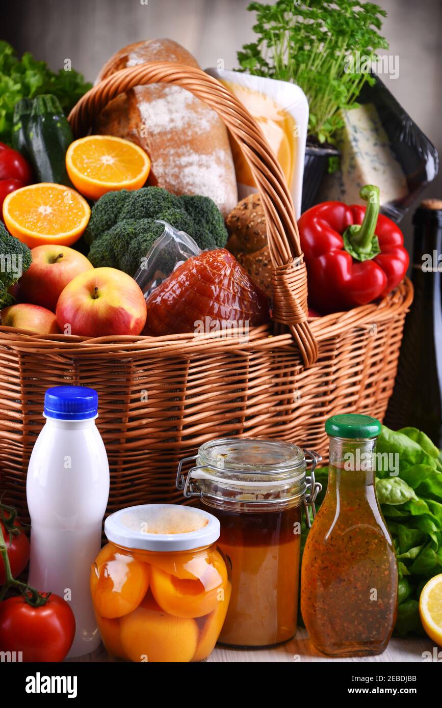 Wicker basket with assorted grocery products including fresh vegetables ...