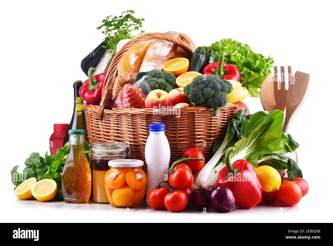 Wicker basket with assorted grocery products including fresh vegetables ...