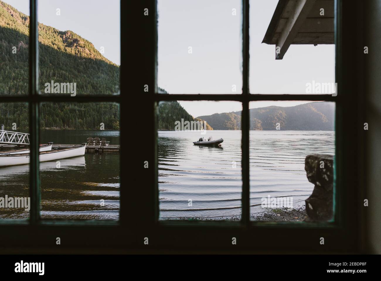 View of lake and boat out of rustic cabin window in the early morning ...