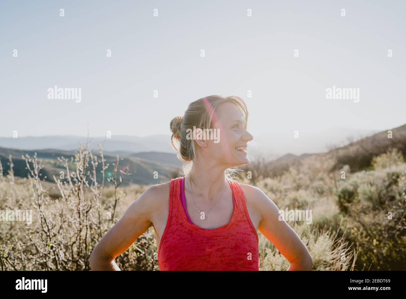 Athletic blonde woman laughs with sun and mountains behind her Stock ...