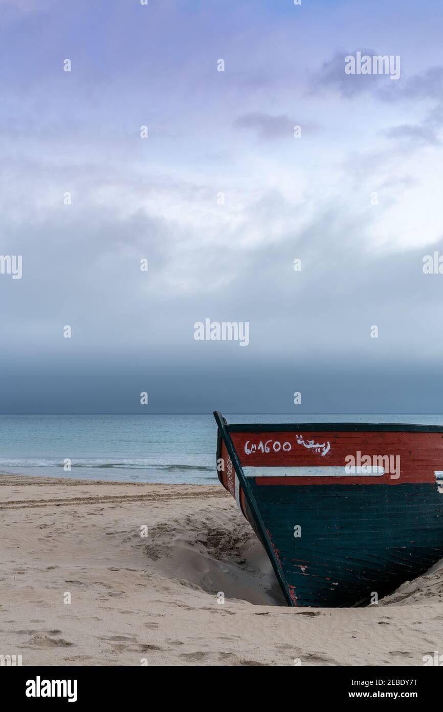 colorful wreck of an old wooden rowboat buried in the sand with an ...