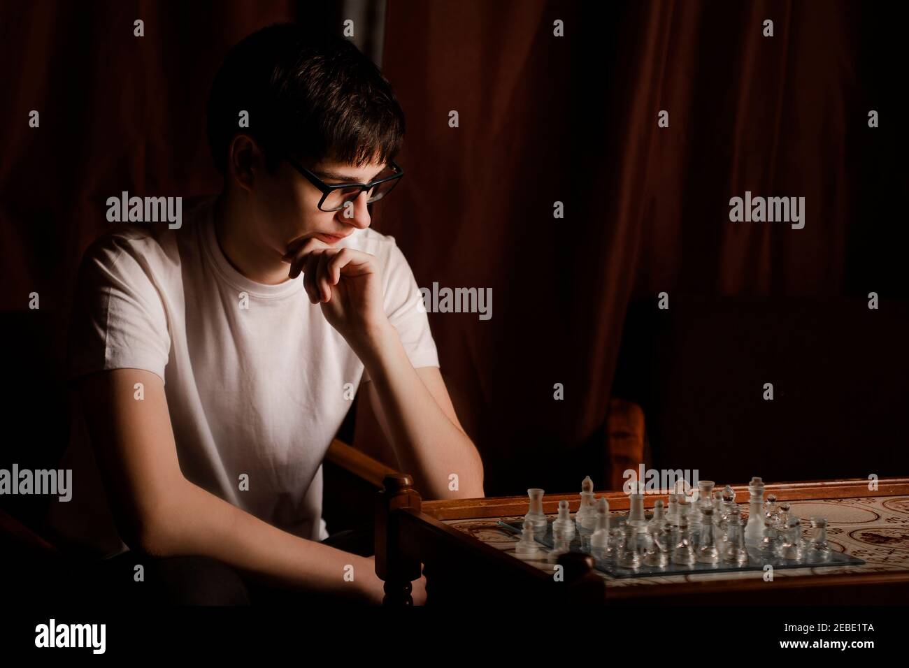 Guy in glasses looking at chess board Stock Photo - Alamy