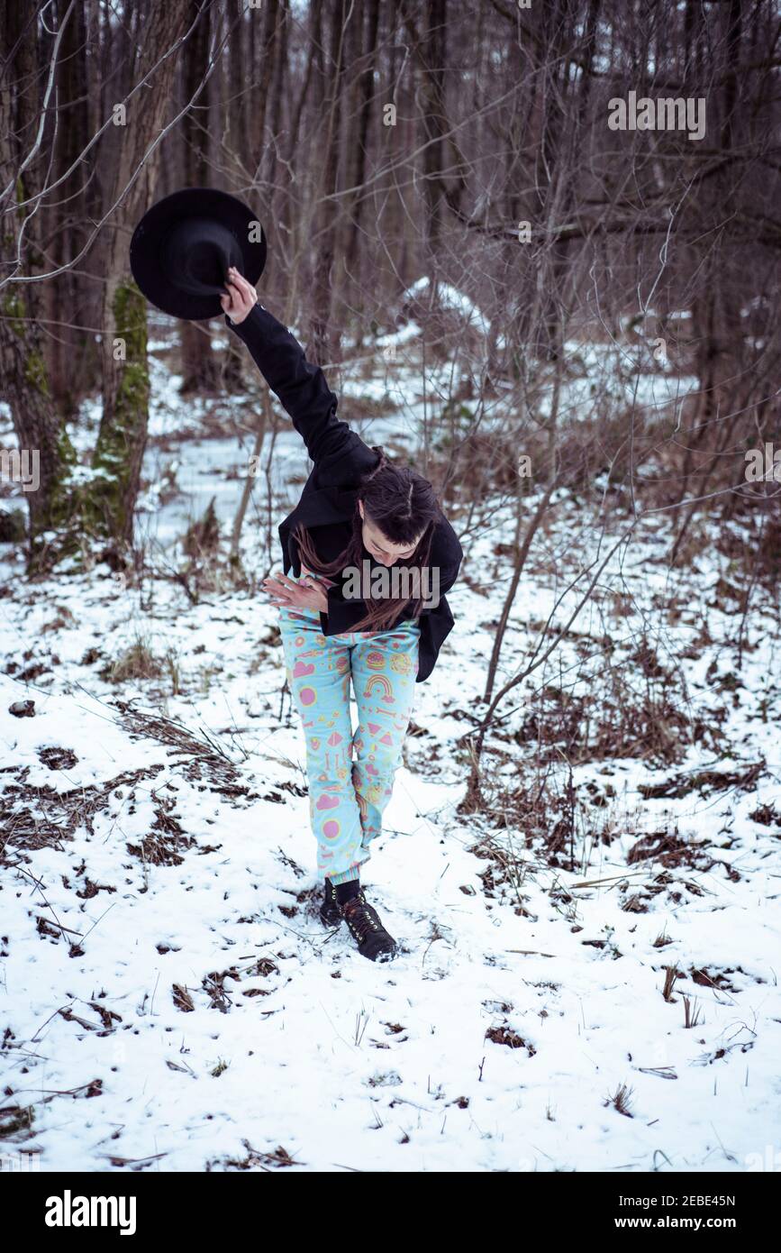 Dancer in tuxedo bows to snow covered forrest with hat in air europe ...
